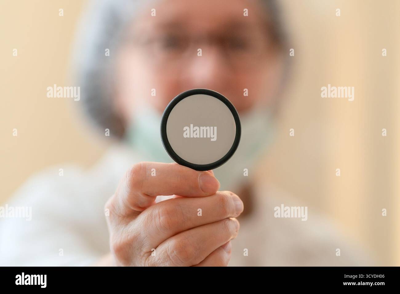 Female doctor in white coat and medical mask holding the stethoscope ...