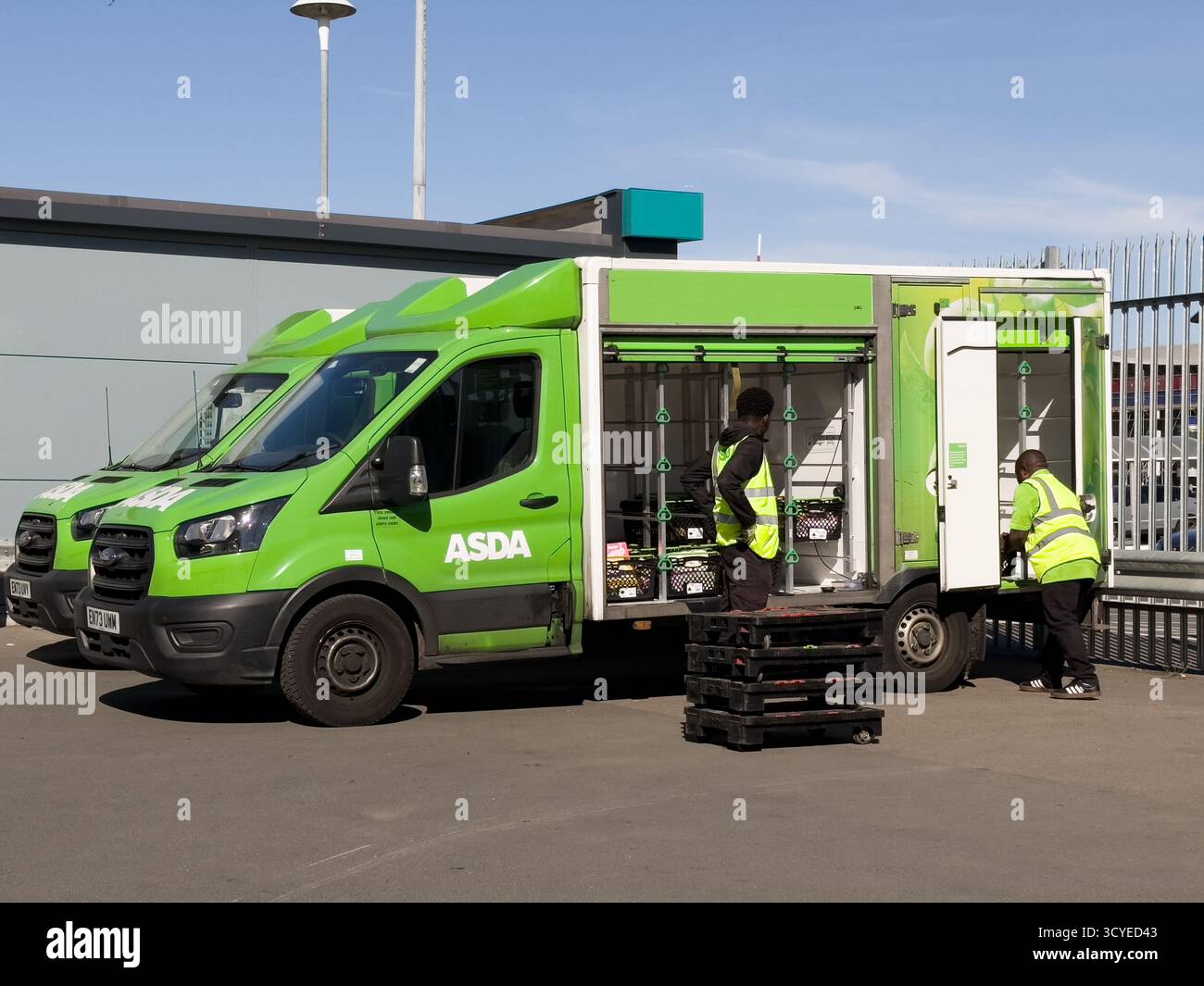 Two ASDA delivery men load customers’ shopping into the side doors of a ...