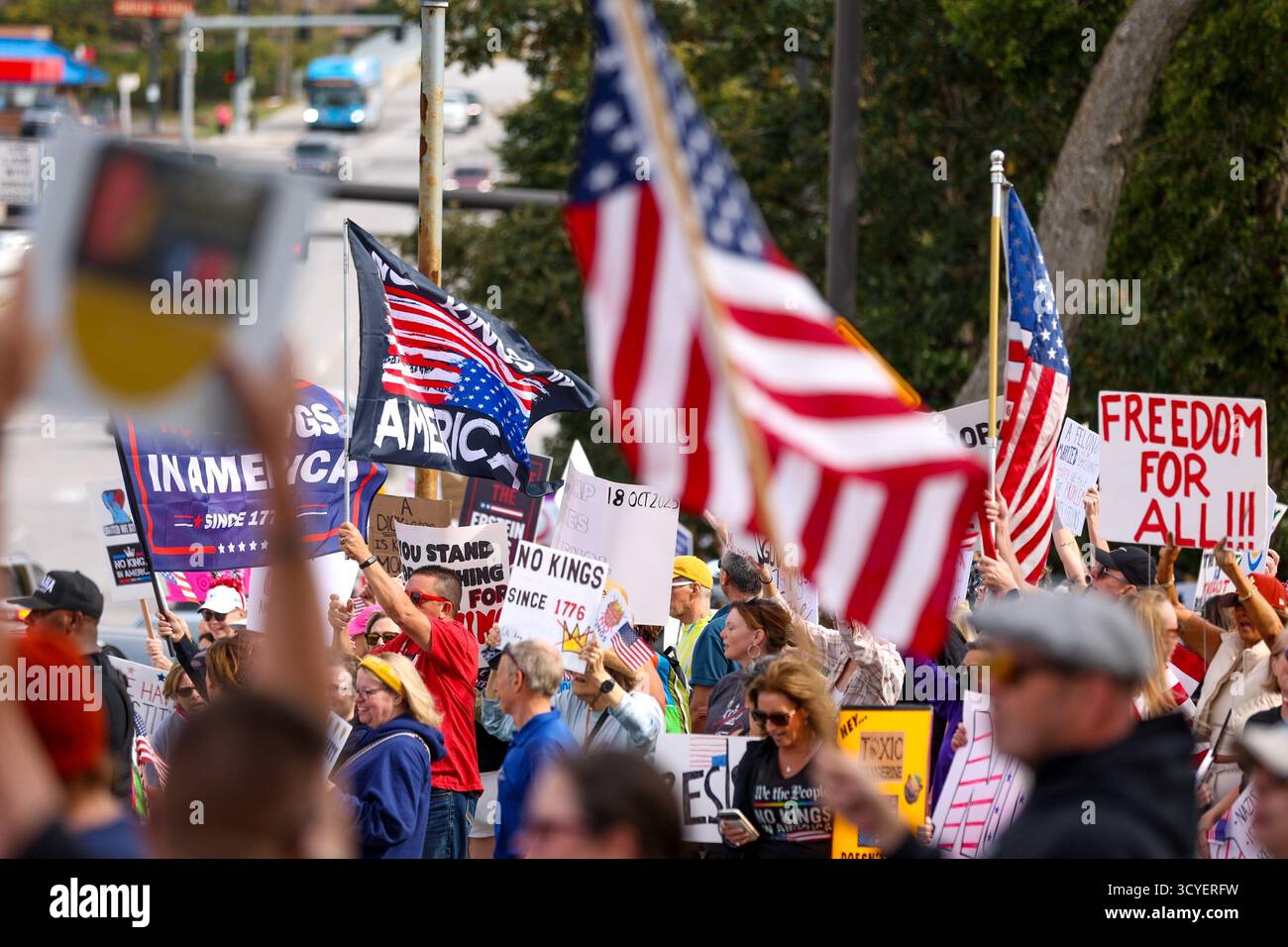 Demonstrators line the sidewalk along Dodge Street during a "No Kings ...