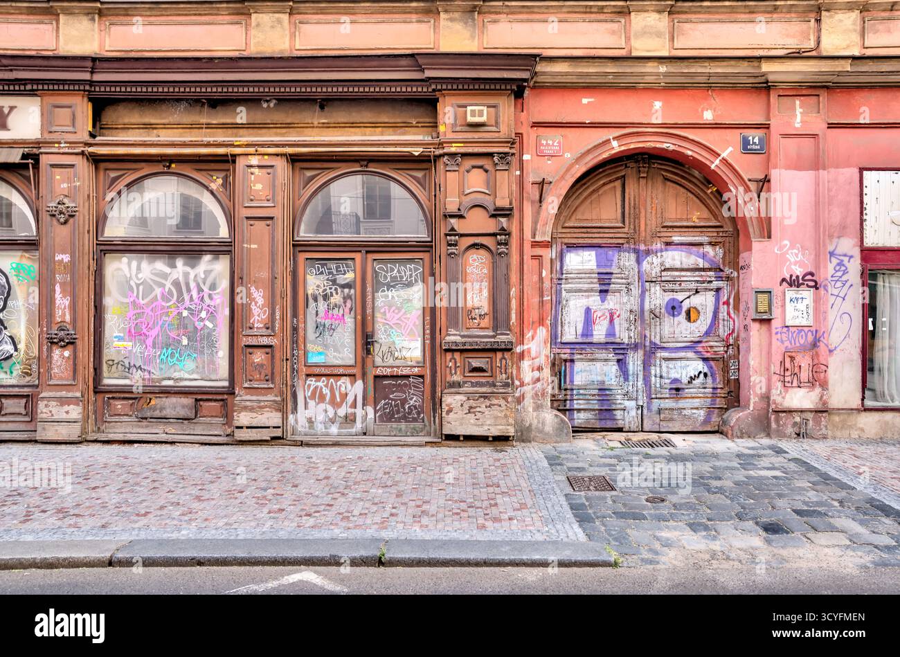 Graffiti-covered storefronts with arched wooden facades and worn doors ...