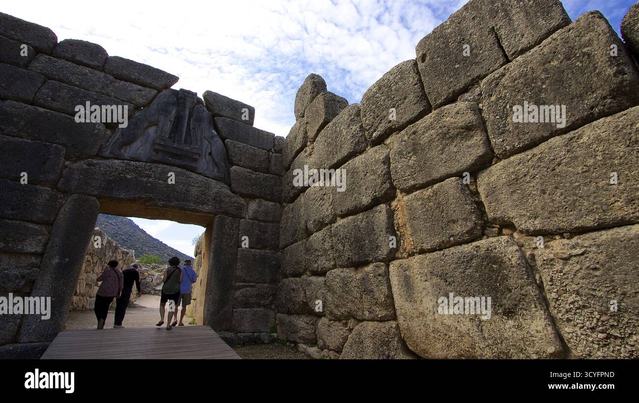 Group of visitors pass through a huge stone gate, lion gate, Mycenae ...