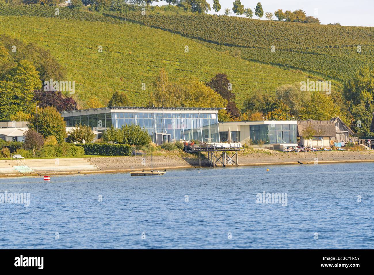 Modern buildings with glass facade nestled in green hills by the water ...