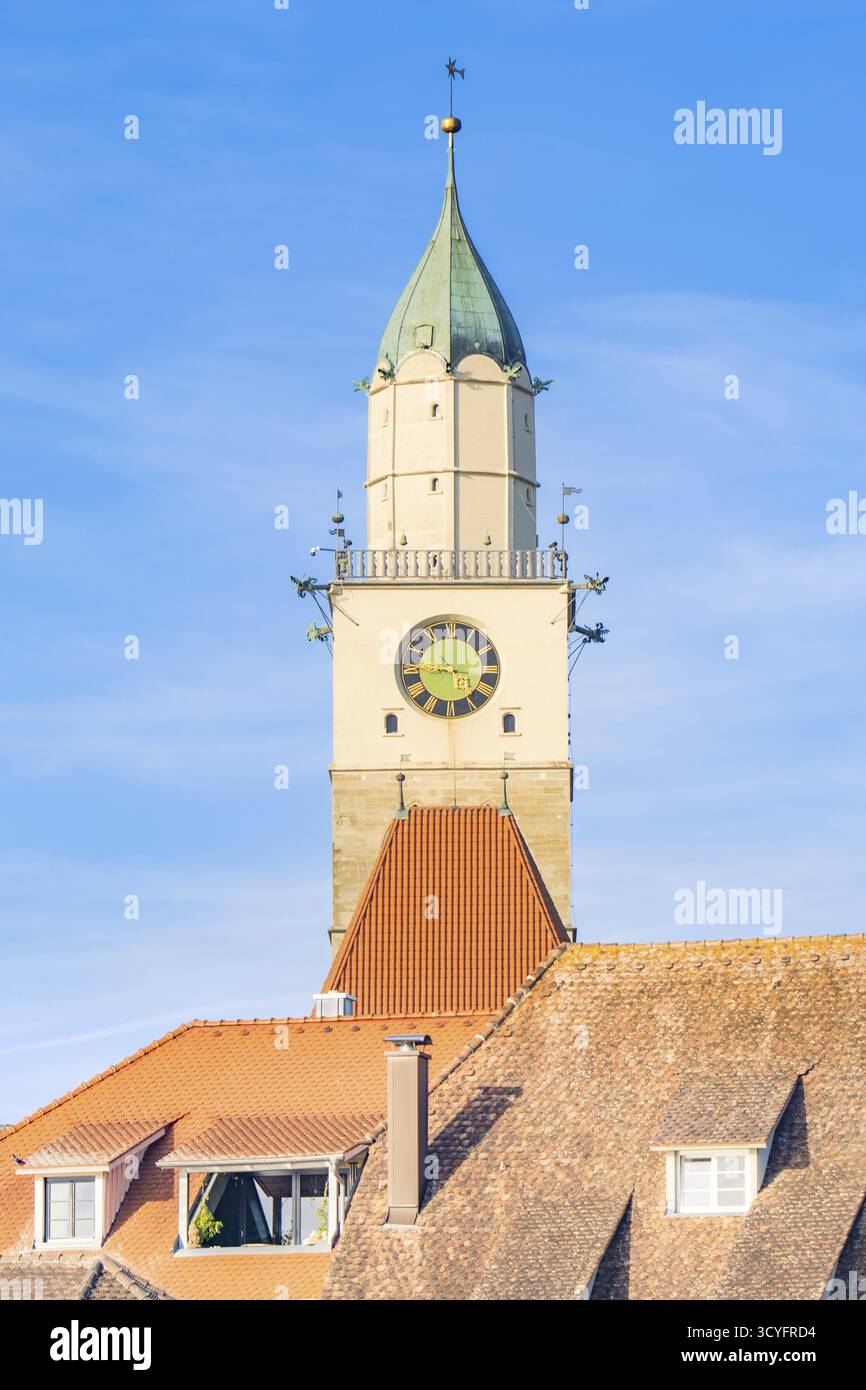 Church tower with clock over red roof tiles under clear blue sky ...