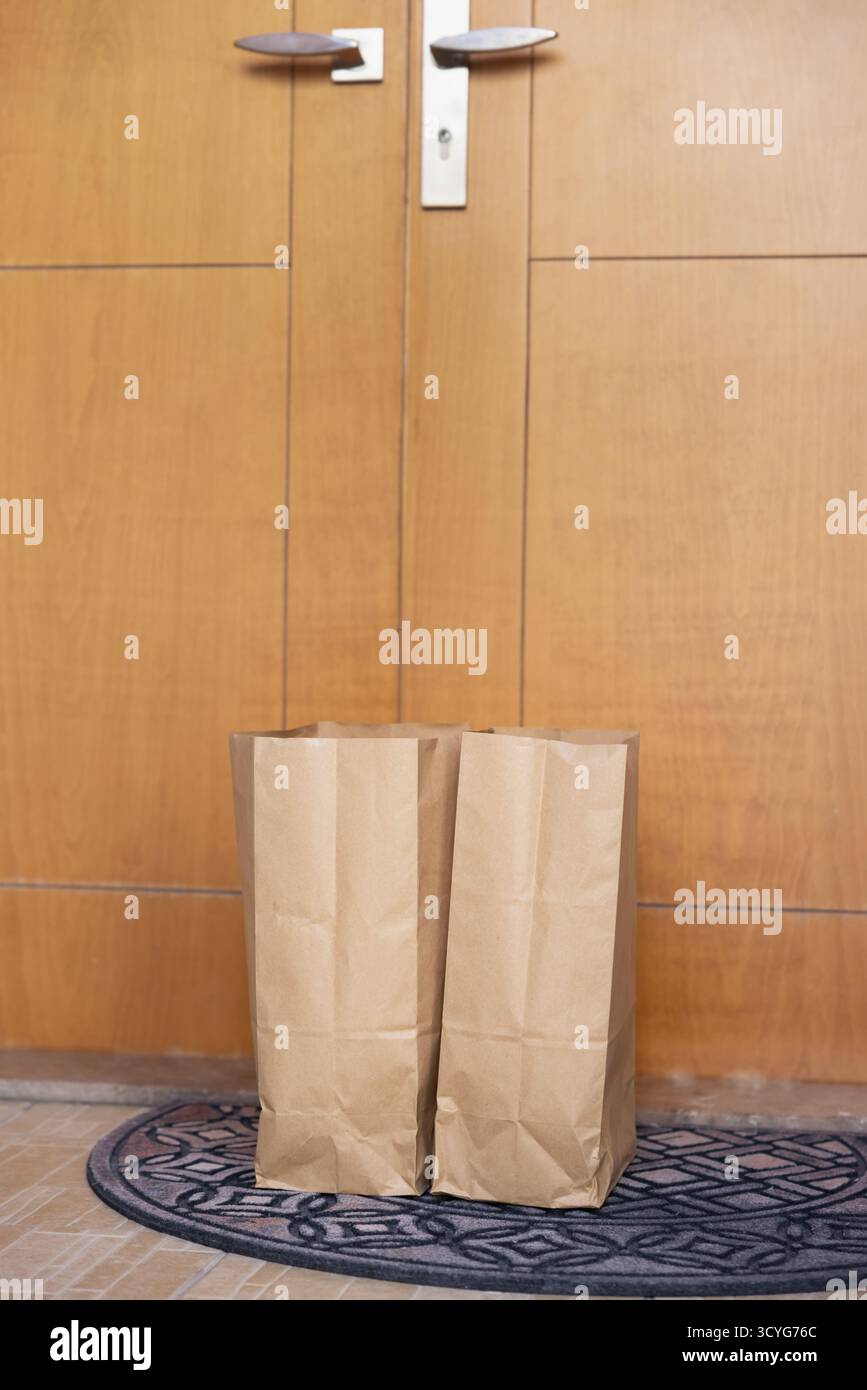 Paper bags with food products waiting for customer by door Stock Photo ...