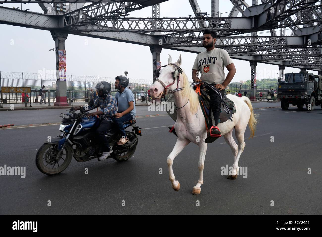 A man rides a horse on the Howrah Bridge besides other vehicles, in ...