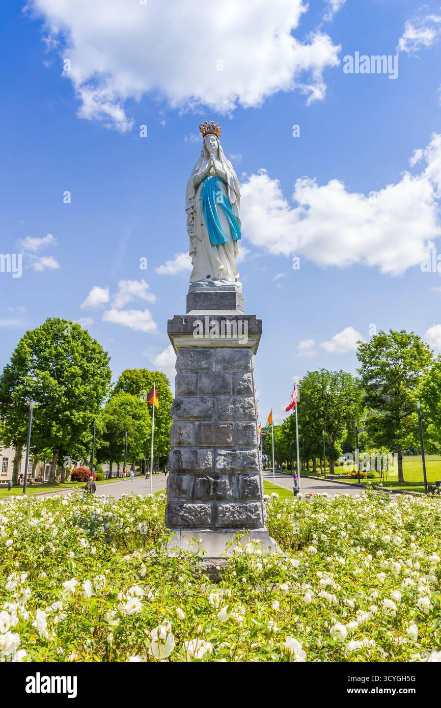 White flowers at the Maria statue in the sanctuary in Lourdes, France ...