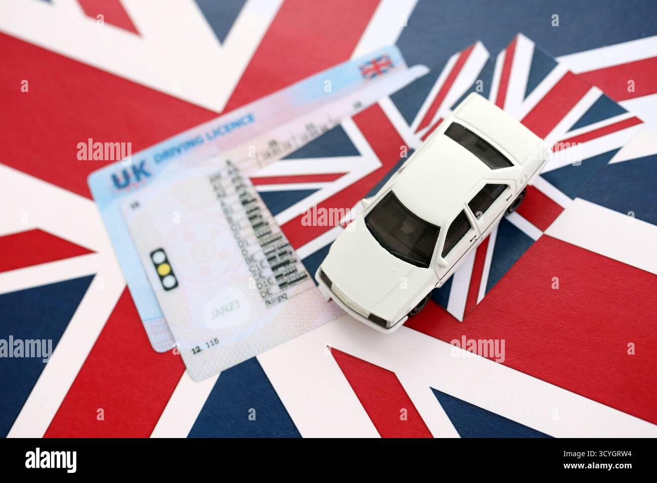 United Kingdom driving license with white toy car on UK flag close up ...