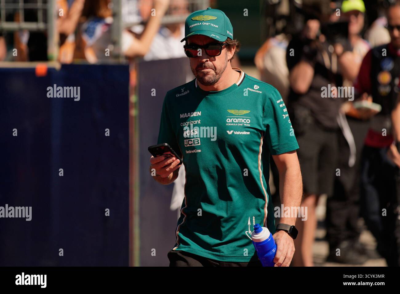Aston Martin driver Fernando Alonso of Spain arrives in the paddock ...
