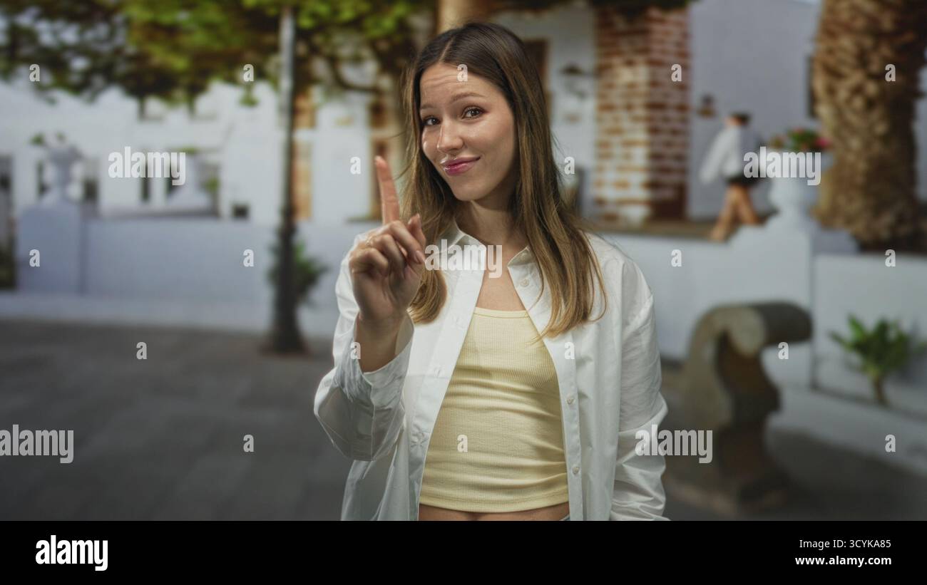 Woman pointing finger on street by a white building and palm trees ...