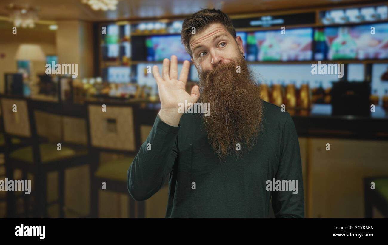 Bearded man lifts hand in wave gesture and glances sideways at ...