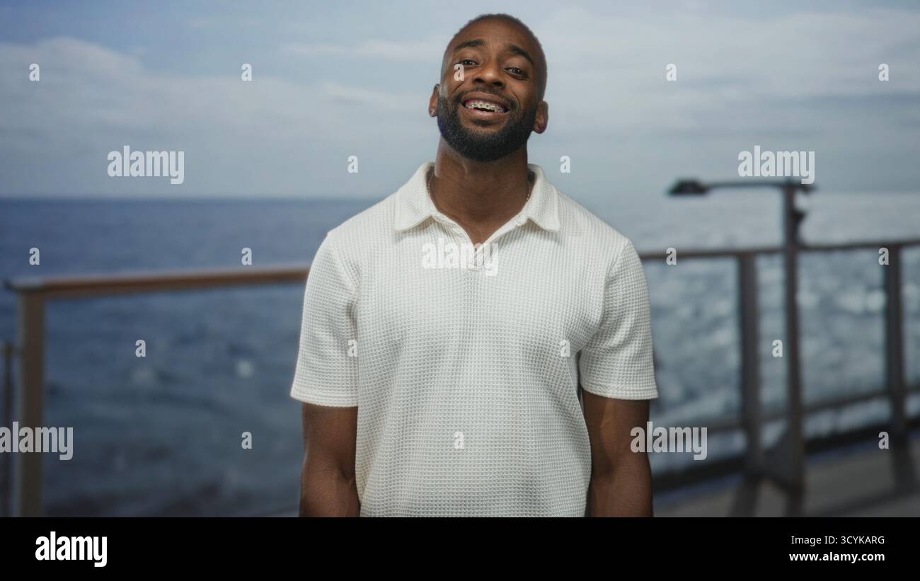 Man tilts head and looks down by a ship railing on a studio set ...
