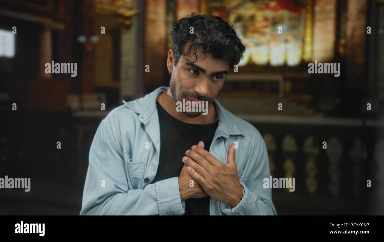 Man clutching chest in dimly lit church under stained glass window ...