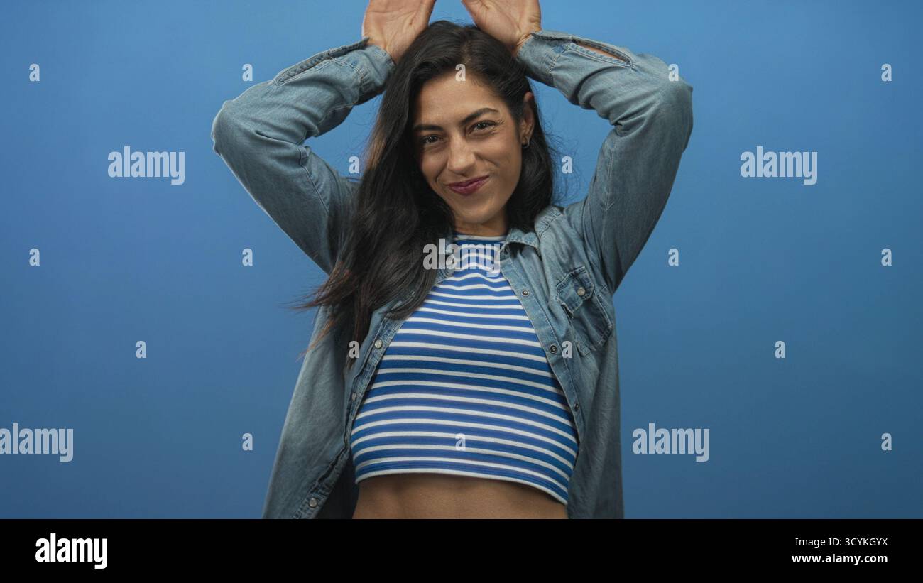 Woman raising hands showing exposed midriff wearing striped crop top ...