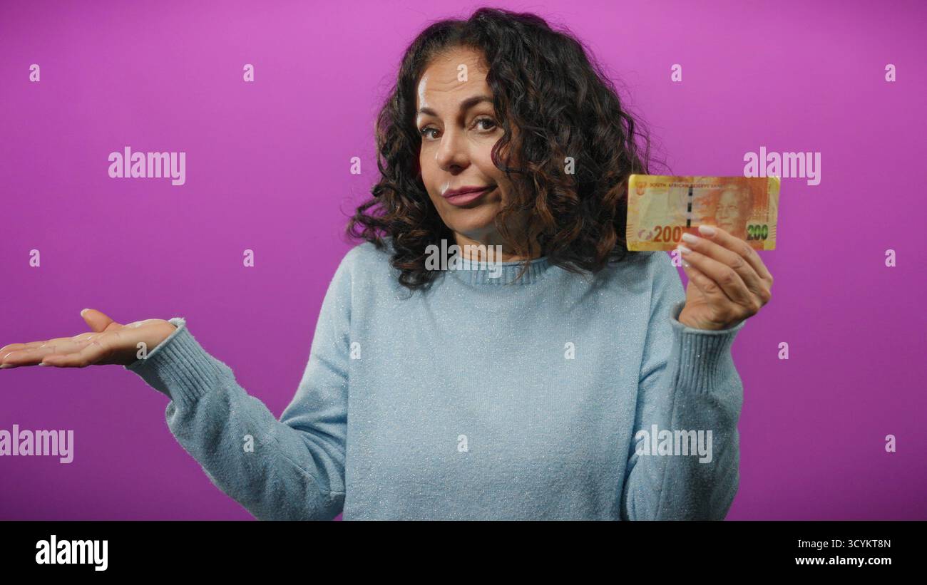 Middle-aged woman holds south african banknote with a puzzled ...