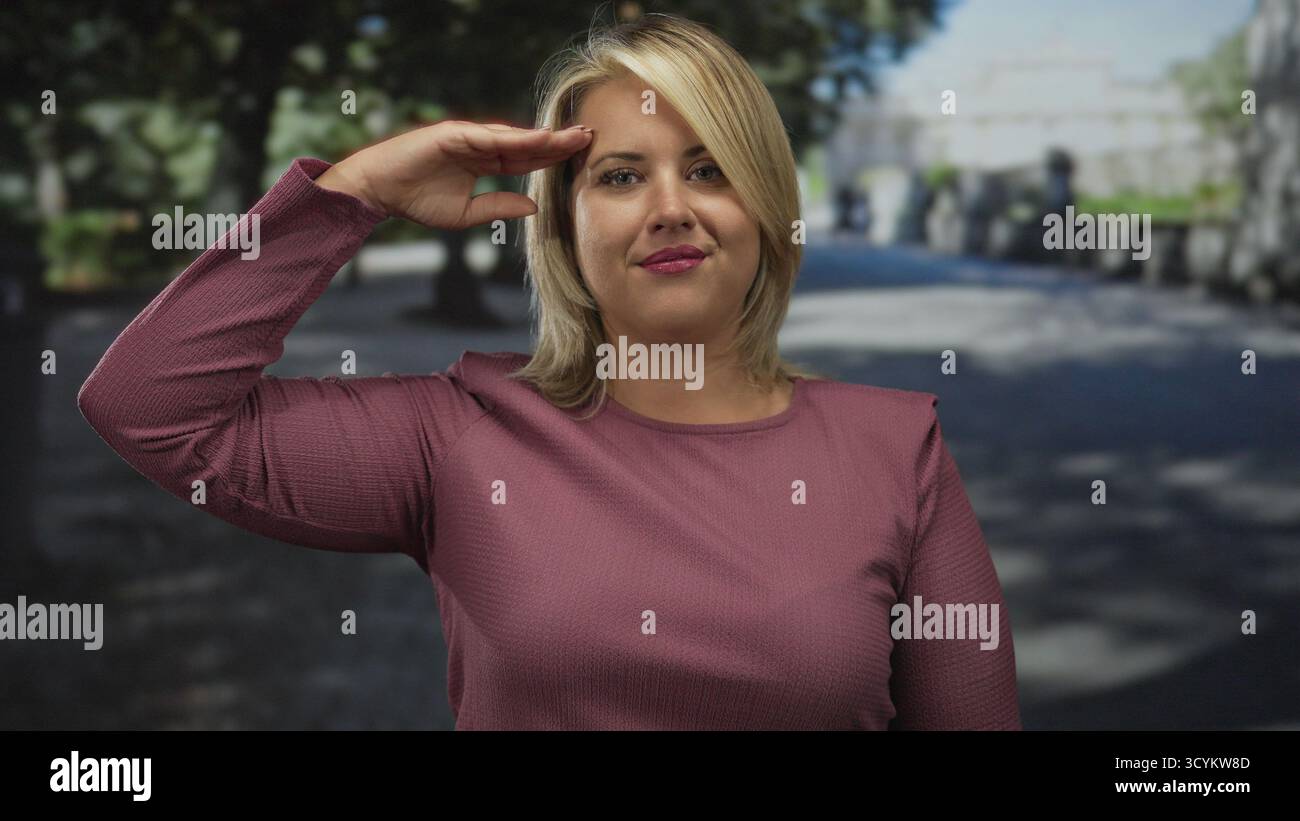 Young blonde woman raises her right hand to forehead in a precise ...