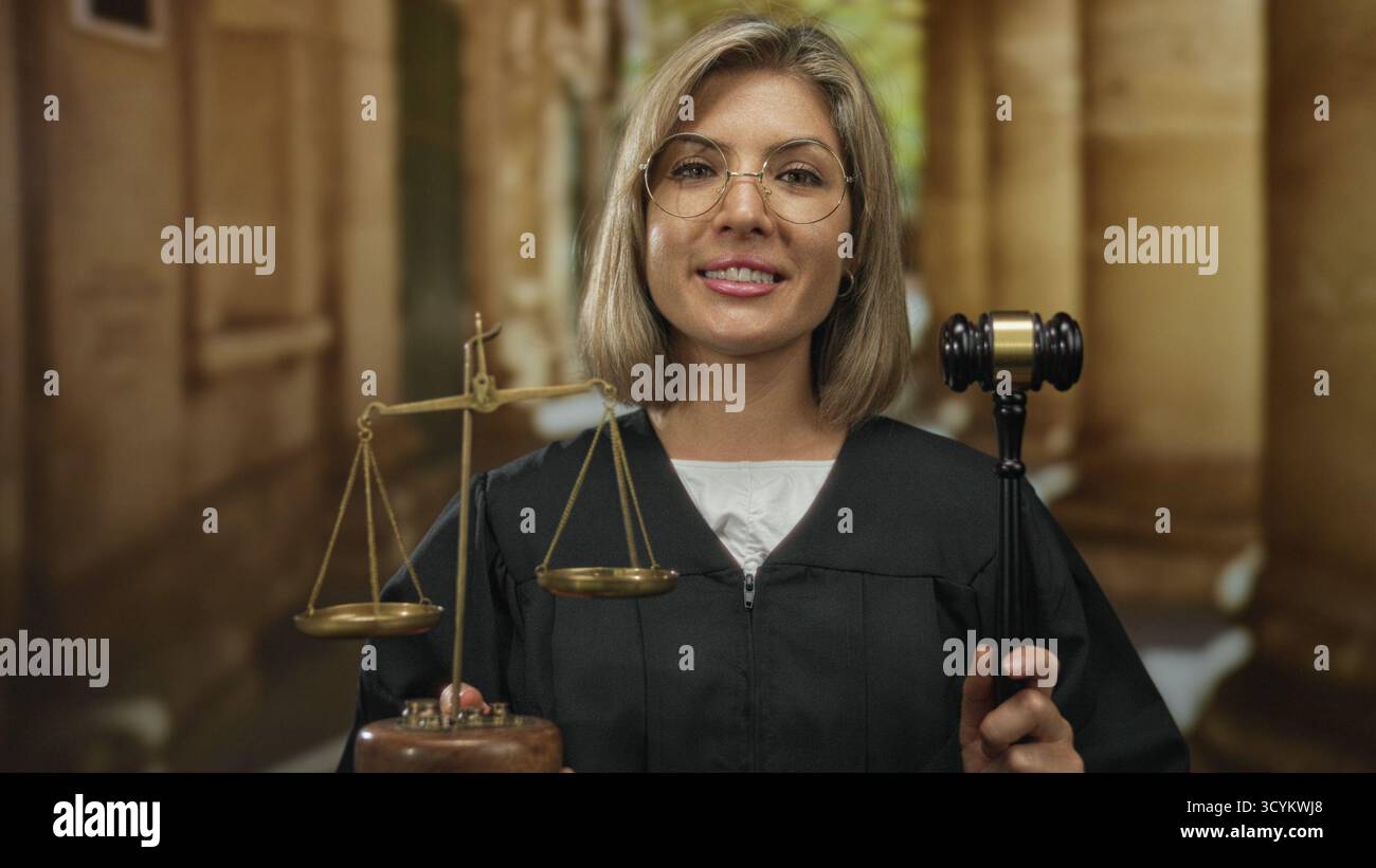 Woman judge in black robe holds golden scales and raises wooden gavel ...