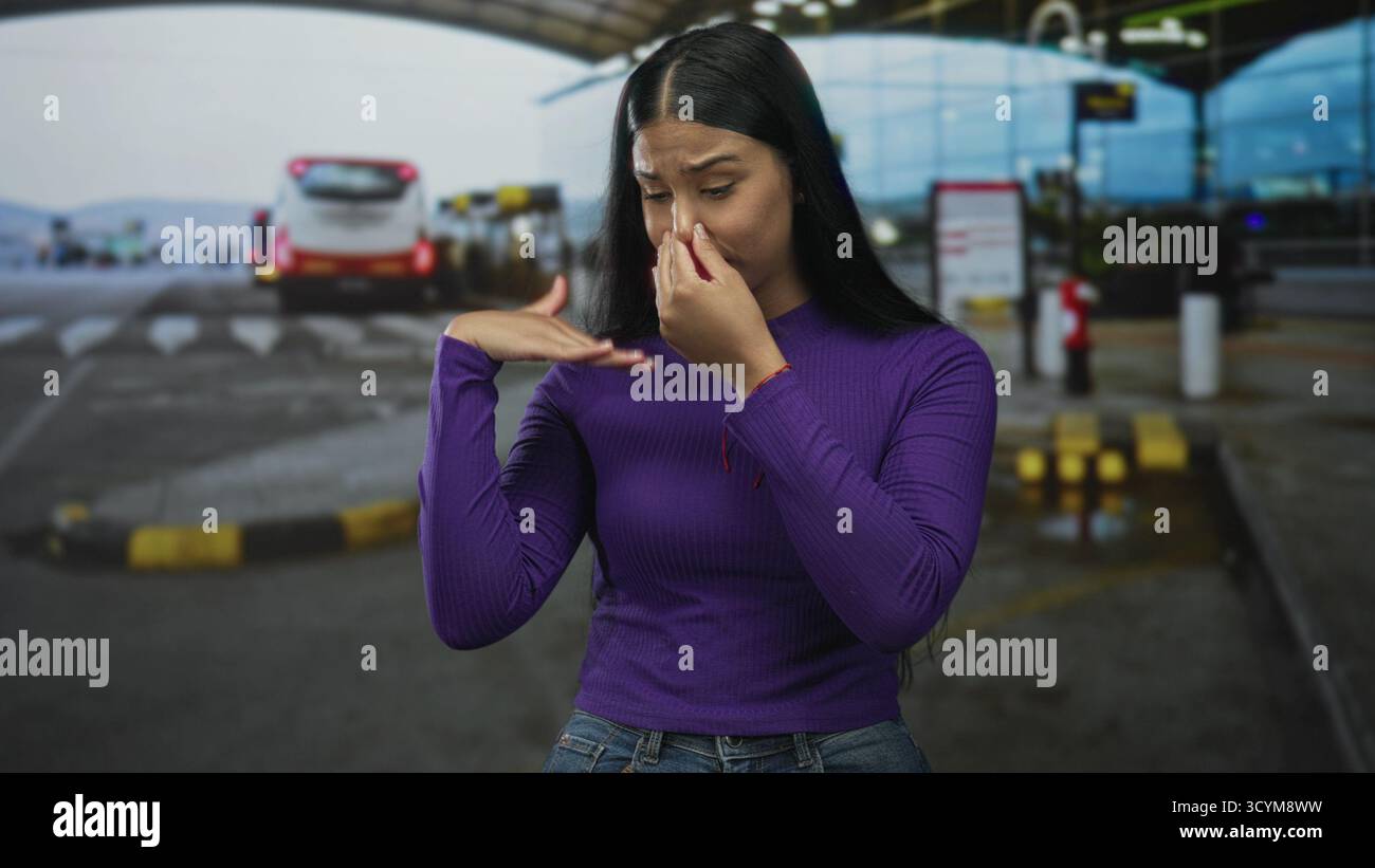 Woman pinches nose with one hand and raises other palm in front of ...