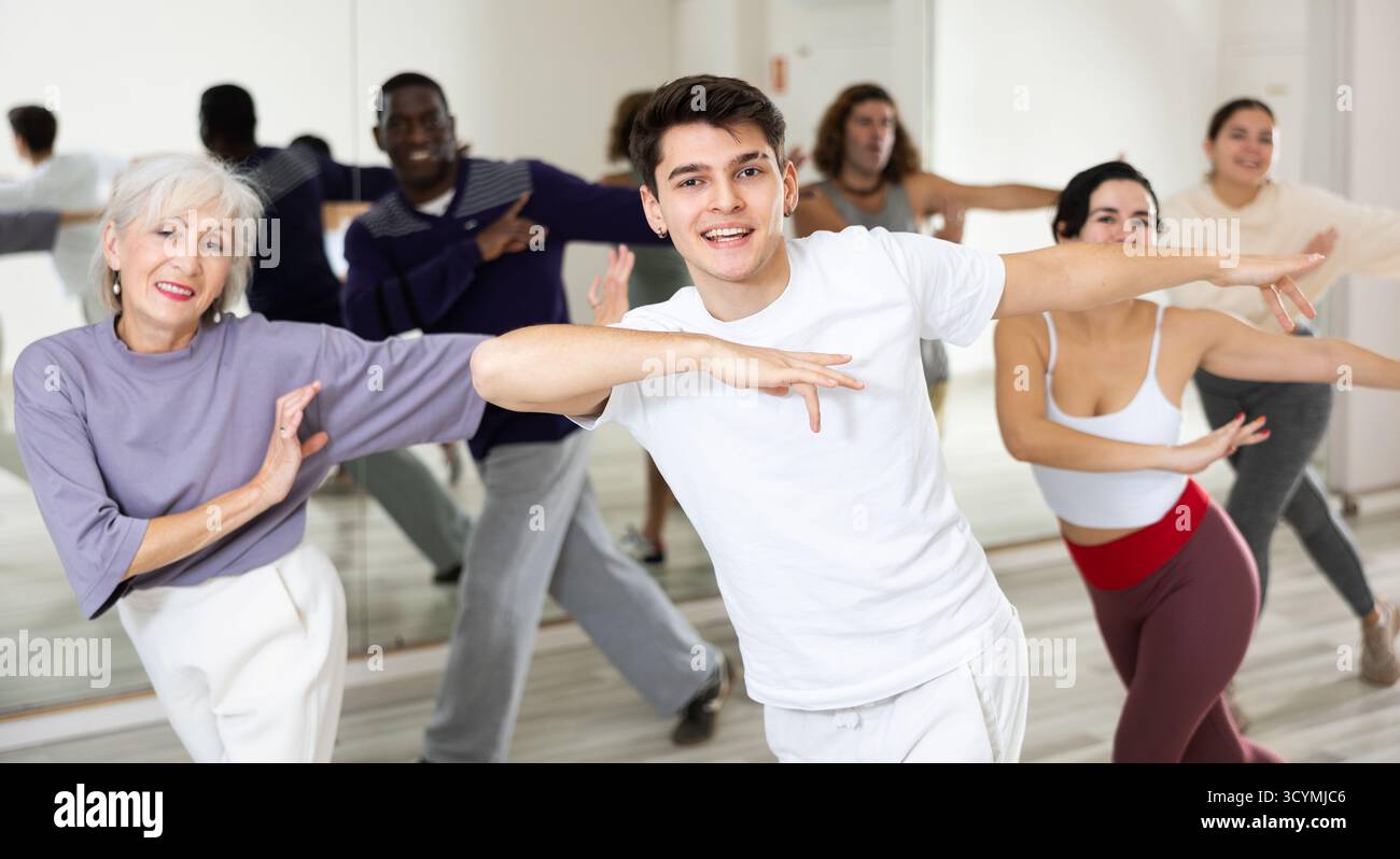 Caucasian guy practising dance moves with other people in dance studio ...