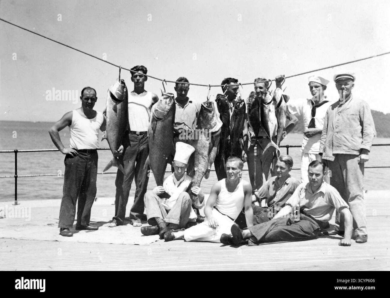 Group of men posing with various captured groupers and mackerel, around ...