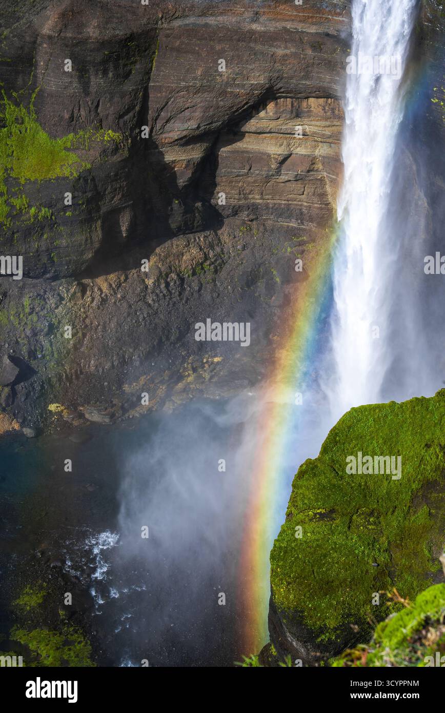 Rainbow arcs through mist at basalt cliff waterfall in Iceland Stock ...