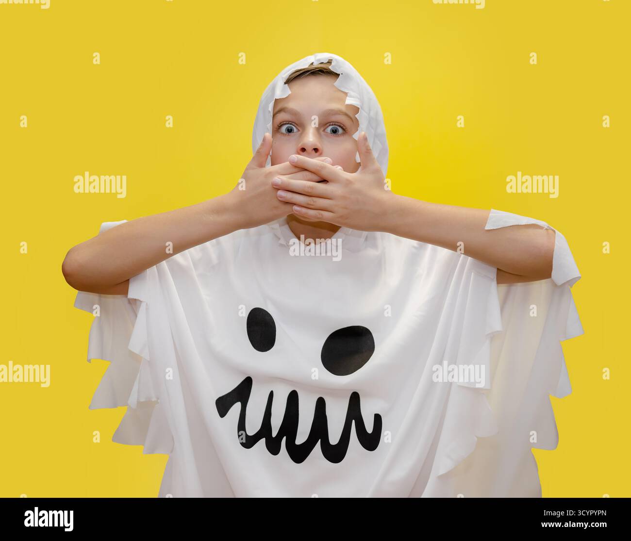 Smiling boy dressed as ghost is pointing upward, standing in front of ...