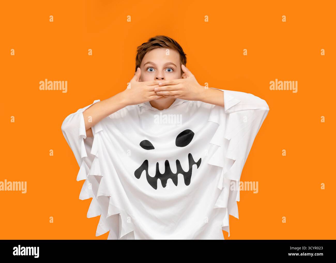 Smiling boy dressed as ghost is pointing upward, standing in front of ...