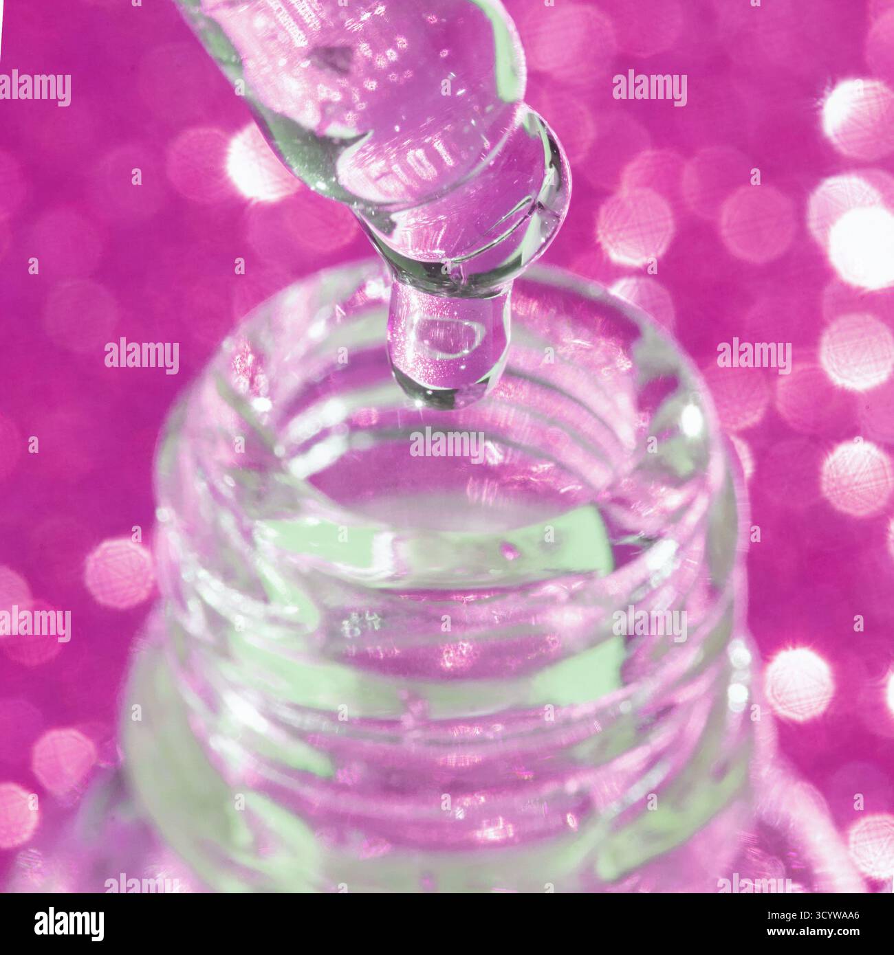 Clear serum droplet falls from dropper into bottle on vibrant pink ...