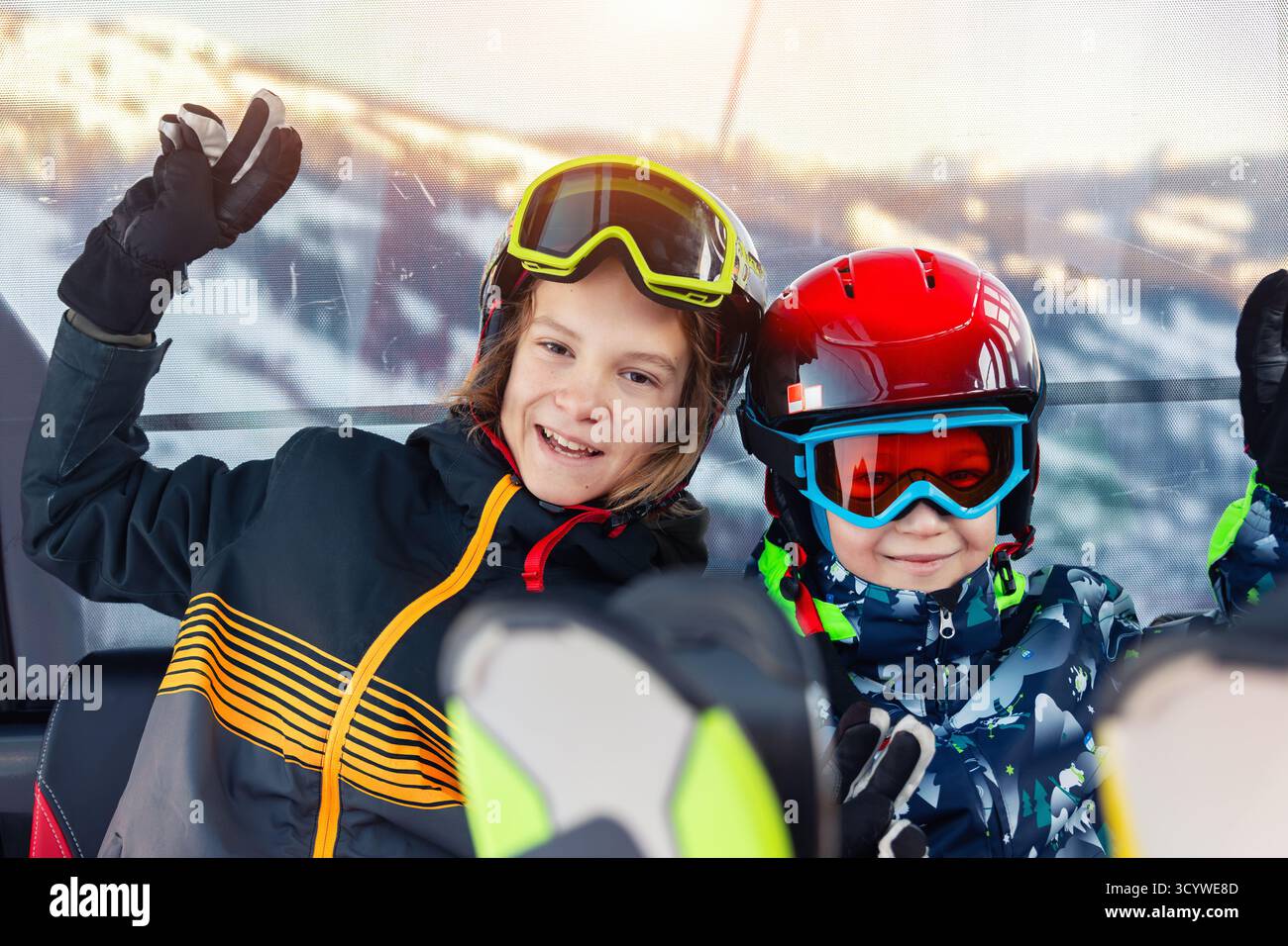 Portrait of two happy kid boys enjoy having fun sit ski lift gondola at ...