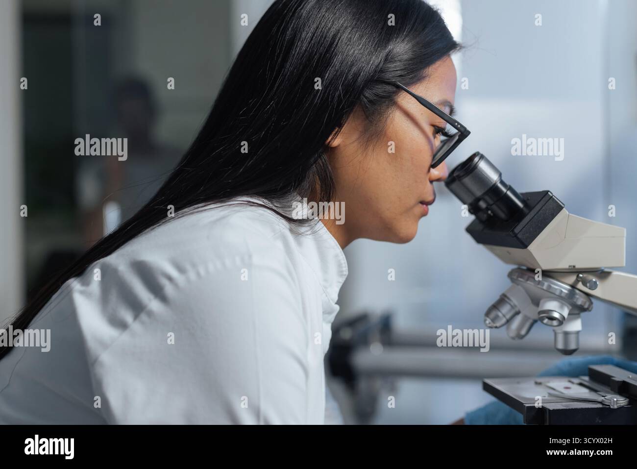 Female lab technician observing a blood sample under the microscope ...