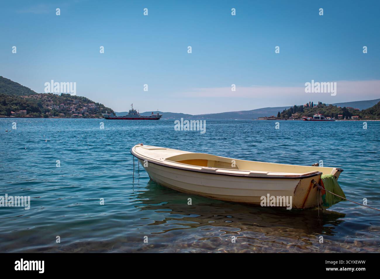 A small white rowboat floating in the clear blue water Adriatic Sea. A ...