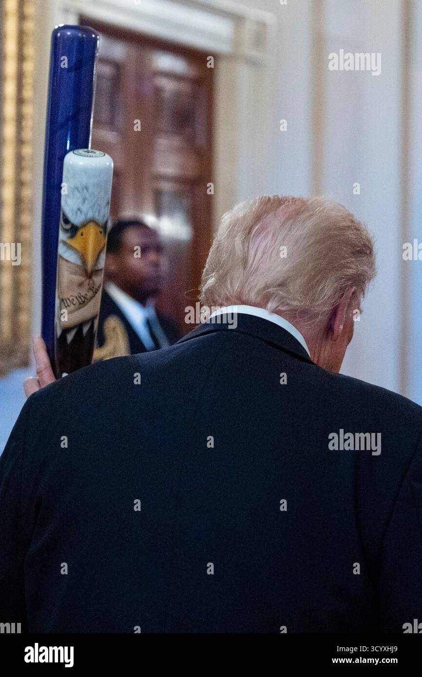 President Donald Trump departs with two bats in hand after an event to ...