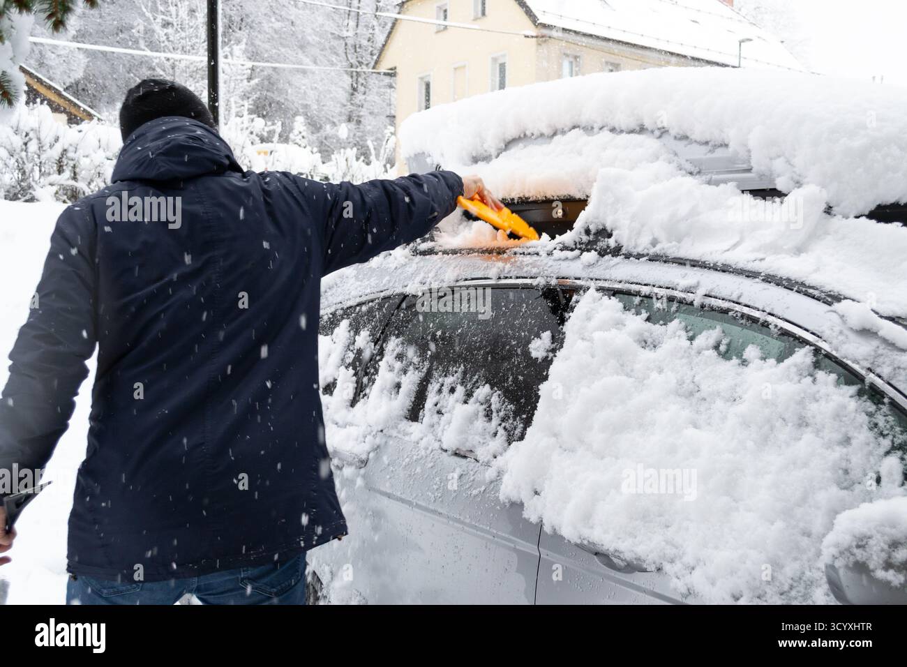 Man cleaning snow from a car during heavy snowfall in winter Stock ...
