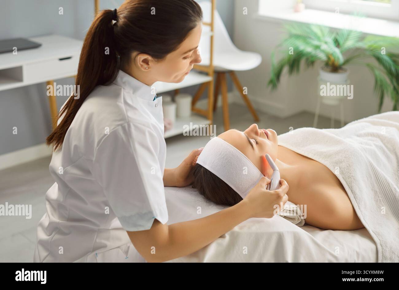 Esthetician performing facial treatment with handheld device in spa ...