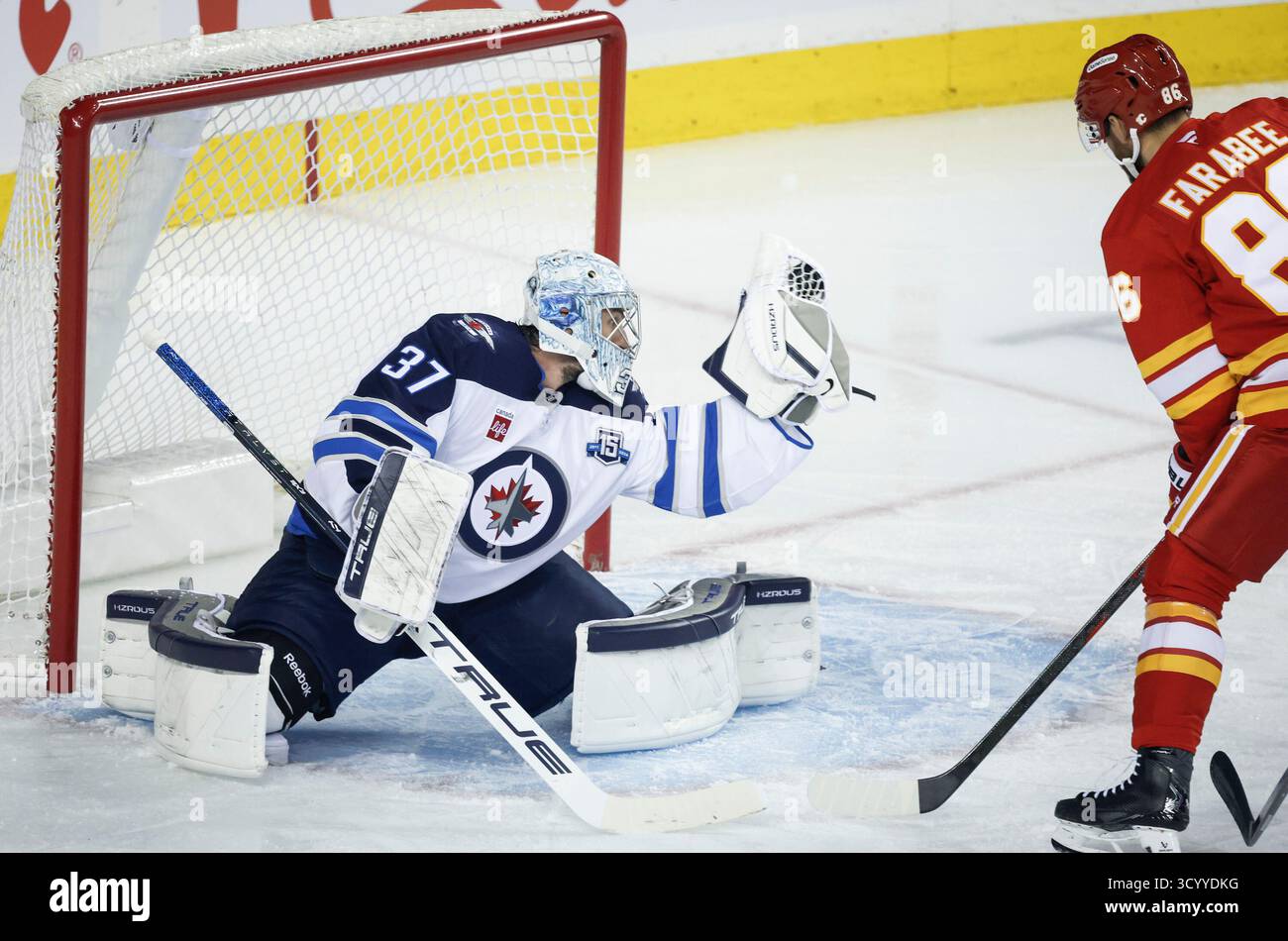 Winnipeg Jets goalie Connor Hellebuyck, left, grabs the puck as Calgary ...