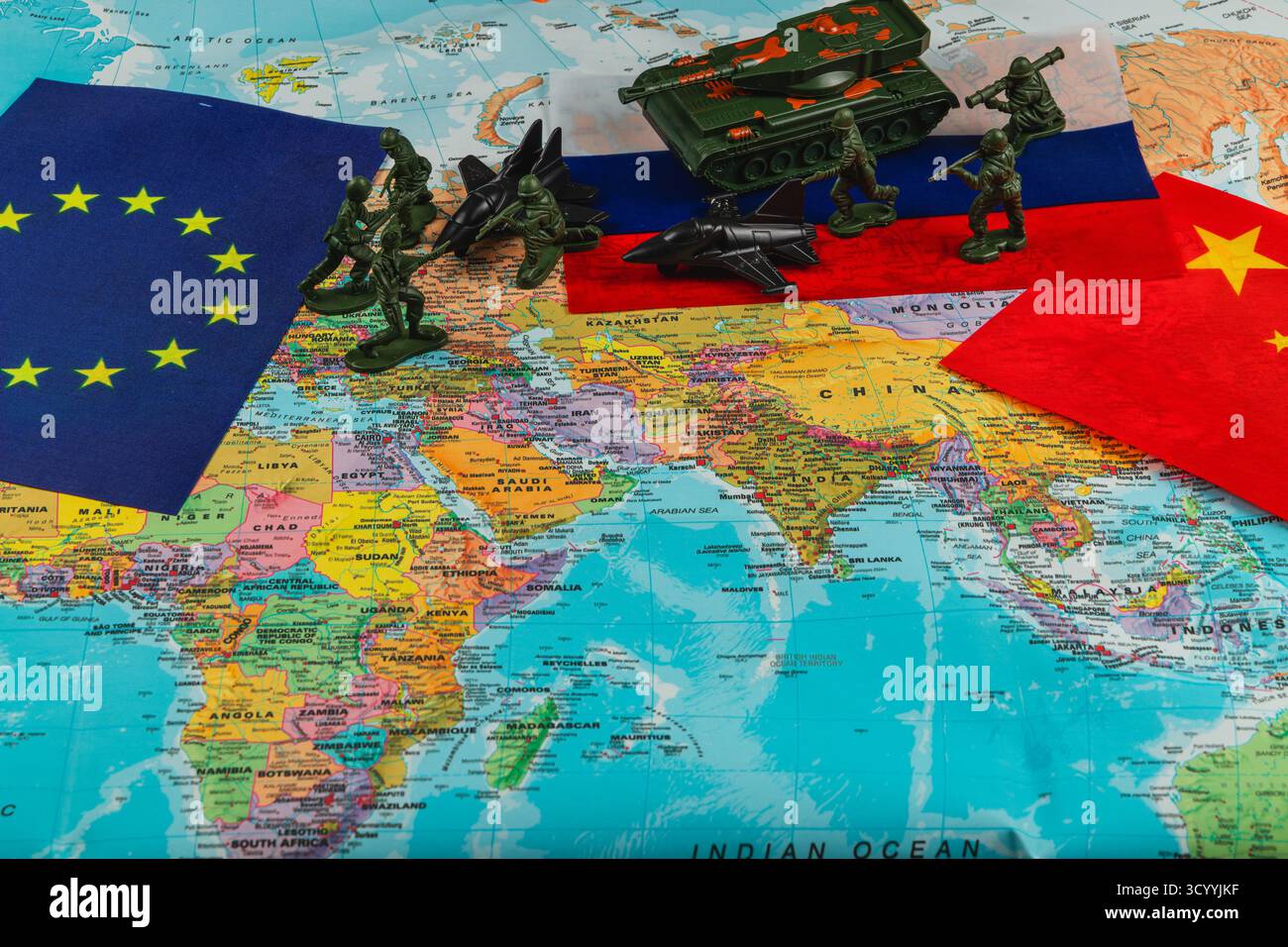 Toy soldiers and military equipment are positioned on a world map, showing flags of Europe ...