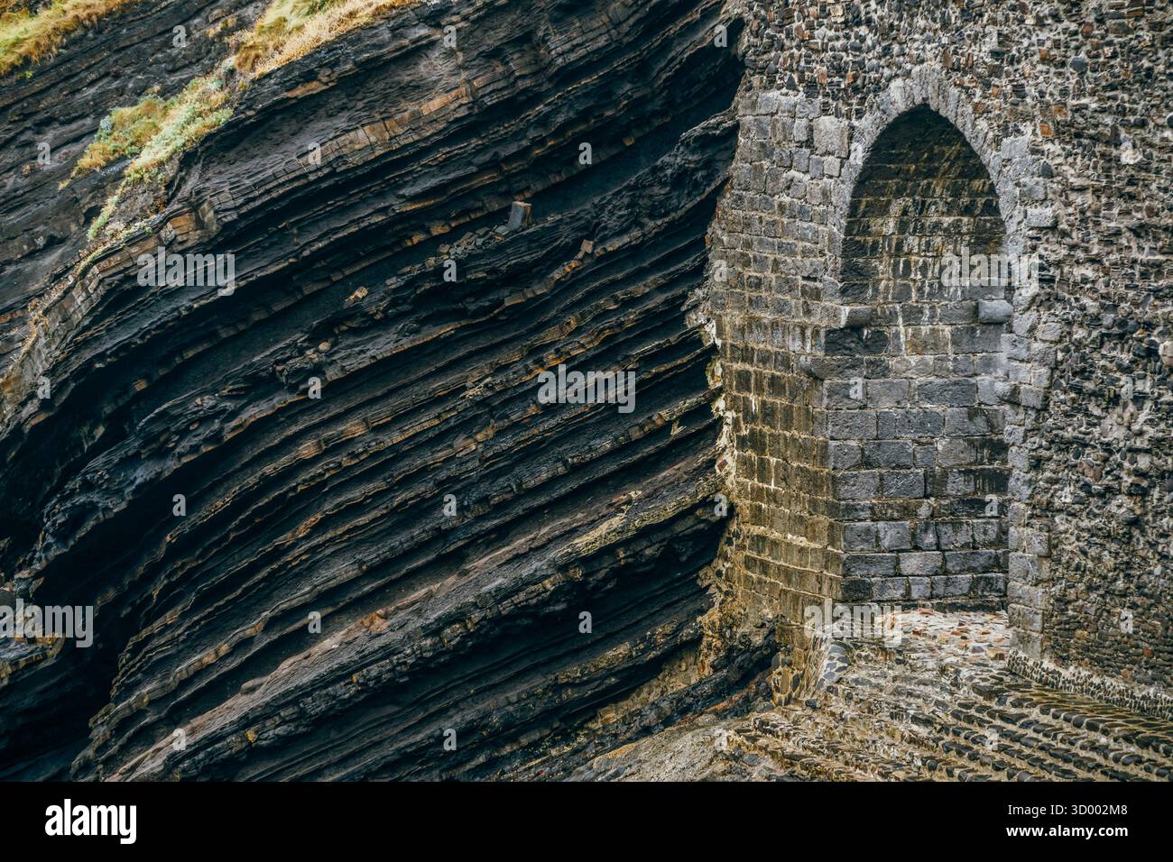 Ancient stone bridge archway merging with dramatic layered sedimentary ...