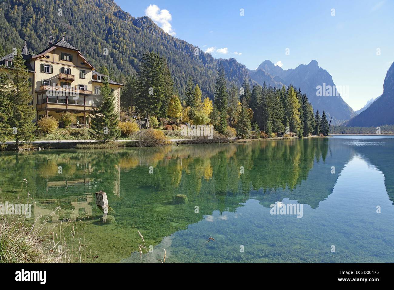 Waterfront villa on a clear mountain lake reflected against rugged ...