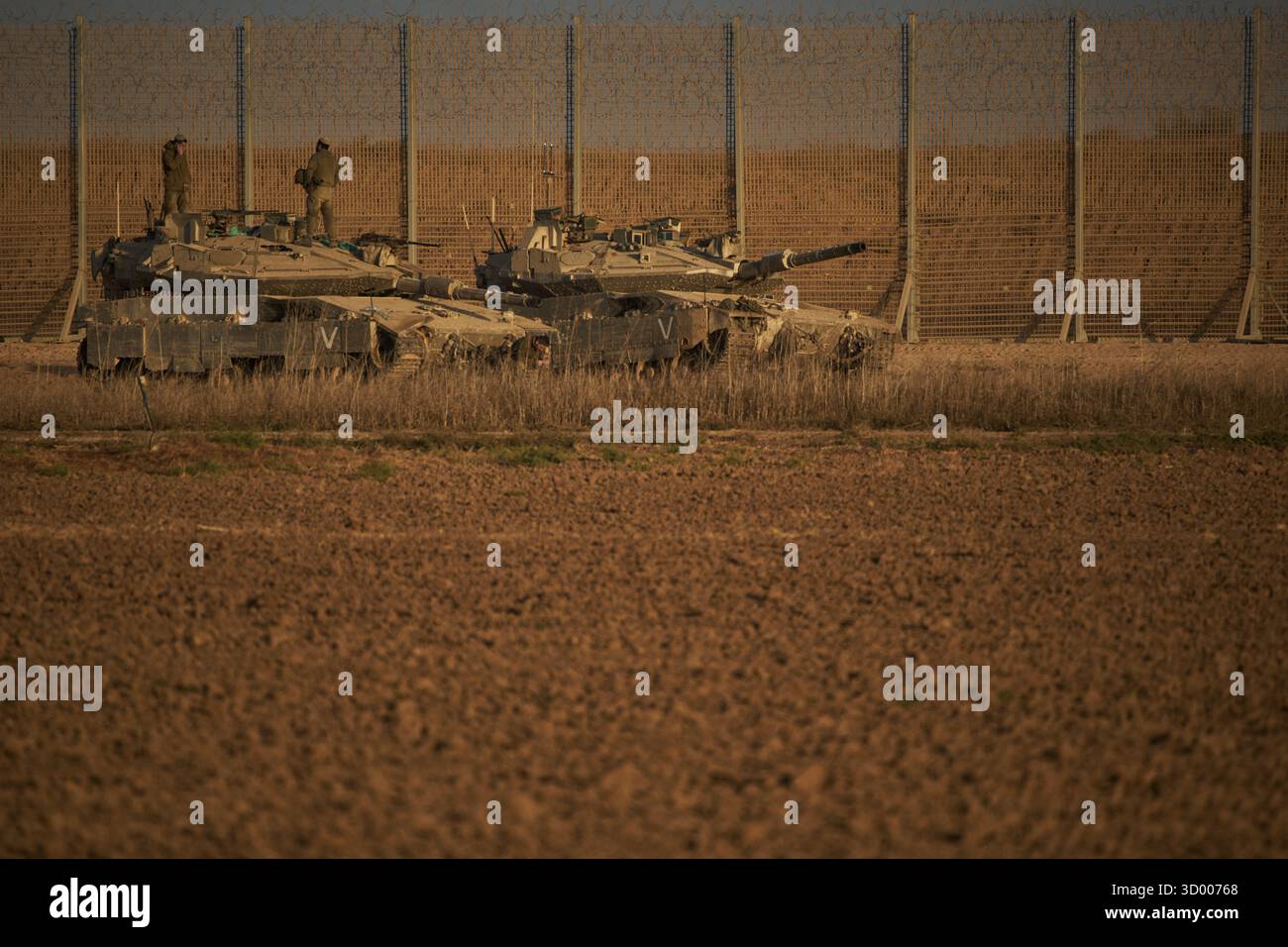 Israeli soldiers standon top of a tank parked in an area at the border ...