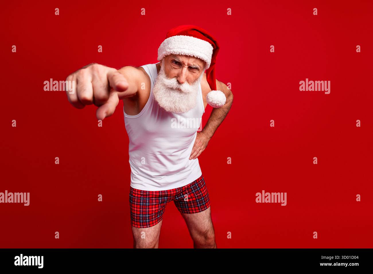 Energetic santa wears white tank top and plaid shorts as he points at ...