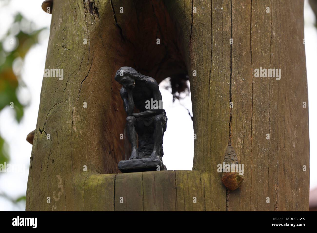 A miniature sculpture of Jesus the Thinker in a niche made of damaged ...