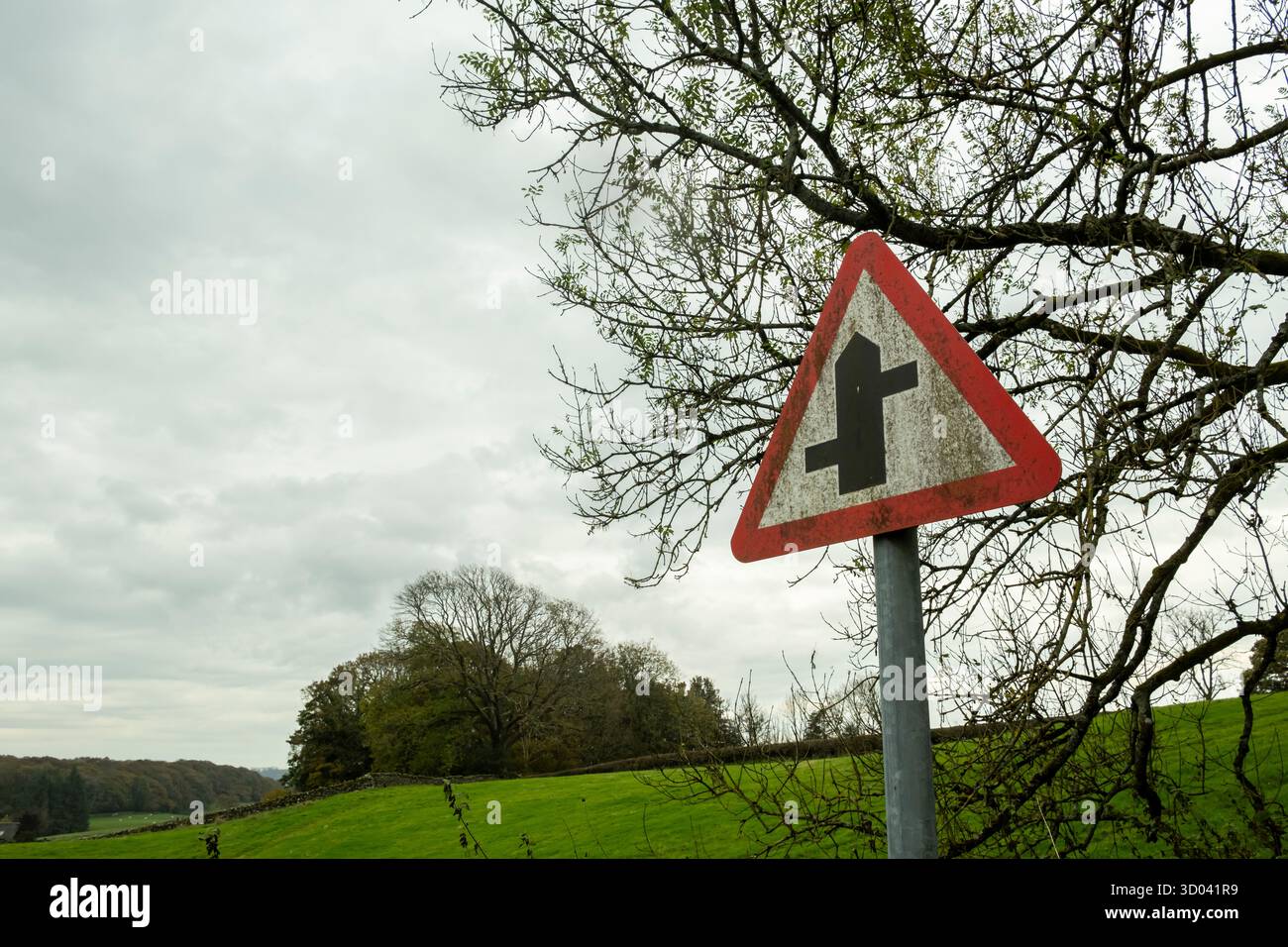 A dirty staggered road junction warning sign triangle Stock Photo - Alamy