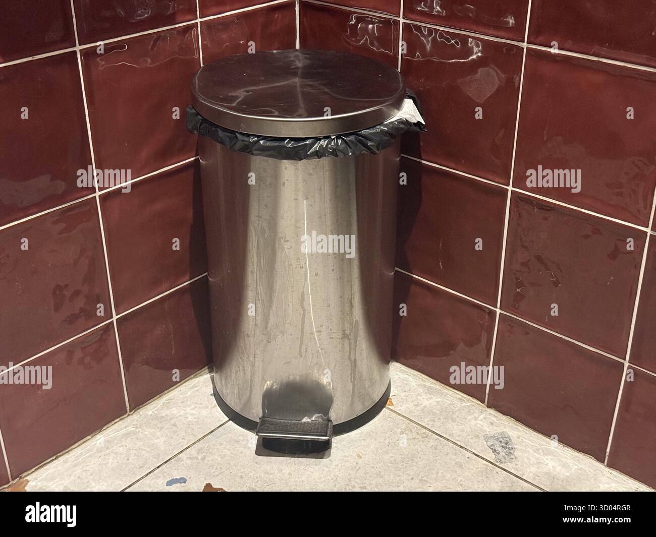 Metal trash bin in restroom corner. Cleanliness, waste management, and ...