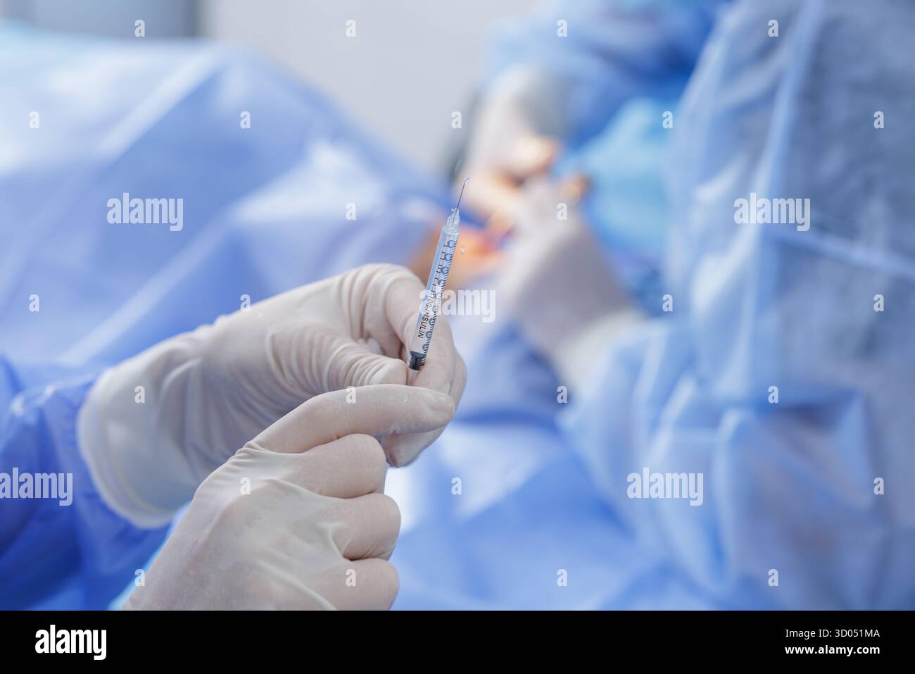 Close view of gloved hands priming a fine syringe for local anesthesia ...
