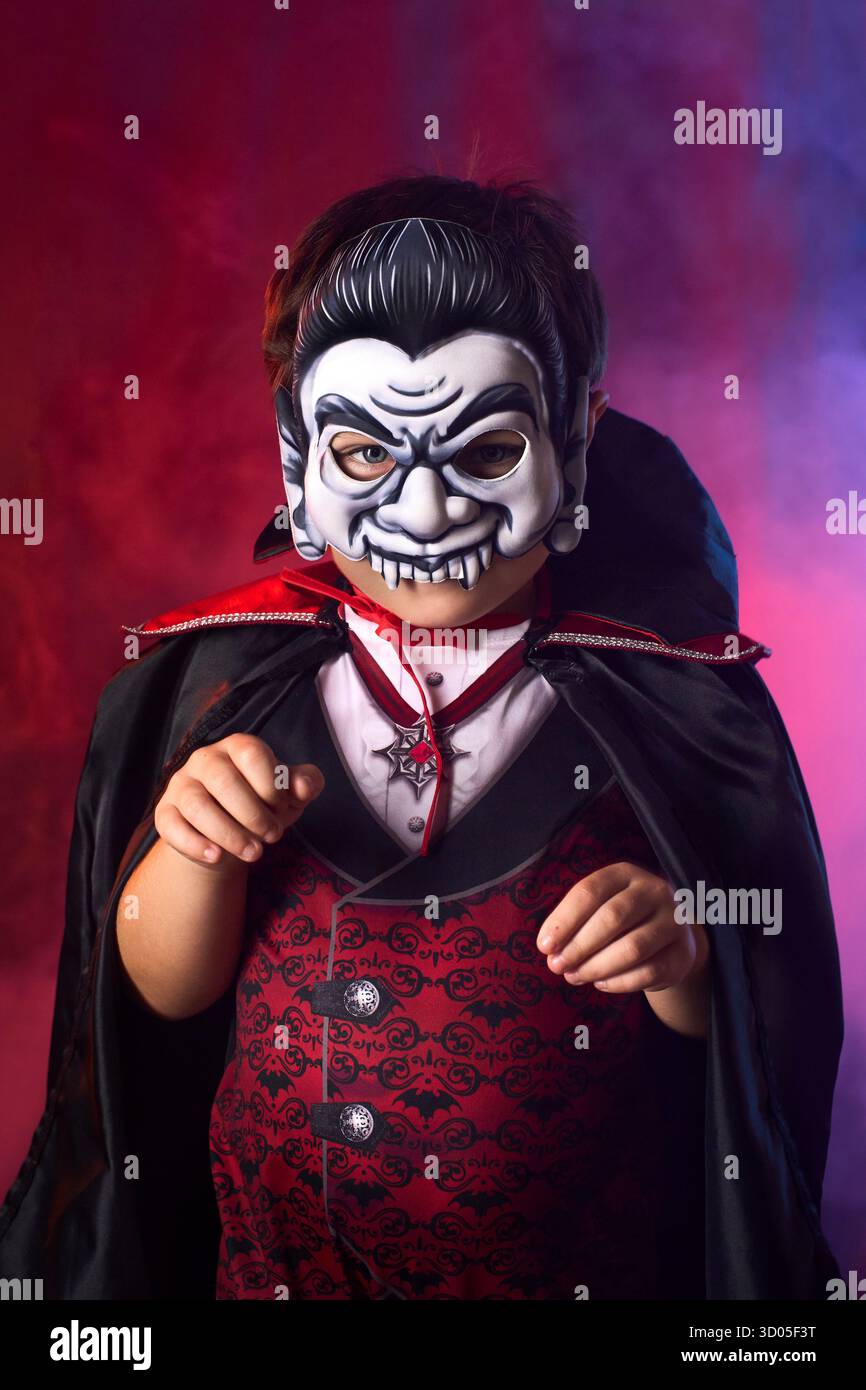 Kid dressed with a vampire costume, with colorful smoke behind him ...