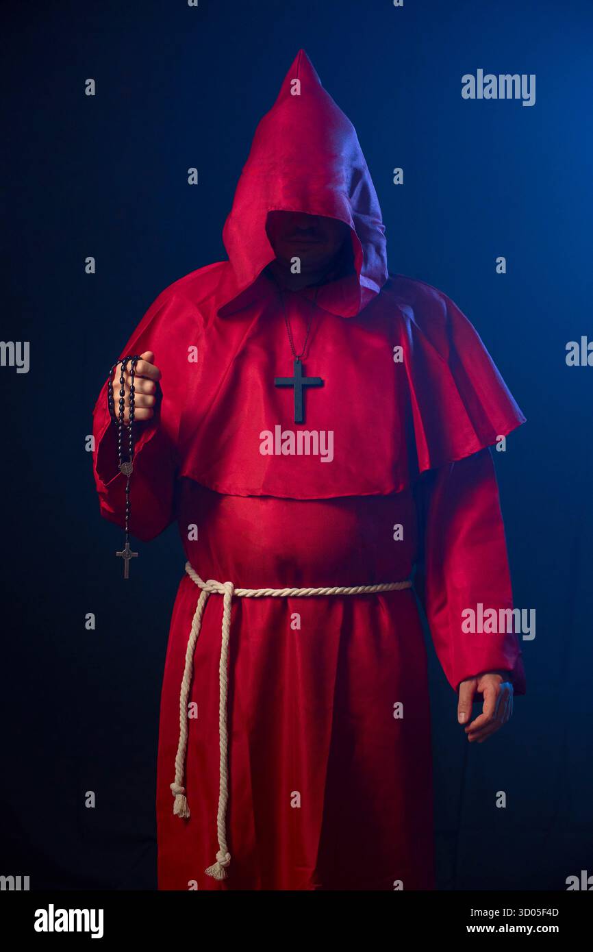Monk with a red robe, a cross in his chest and a prayer beads in his ...