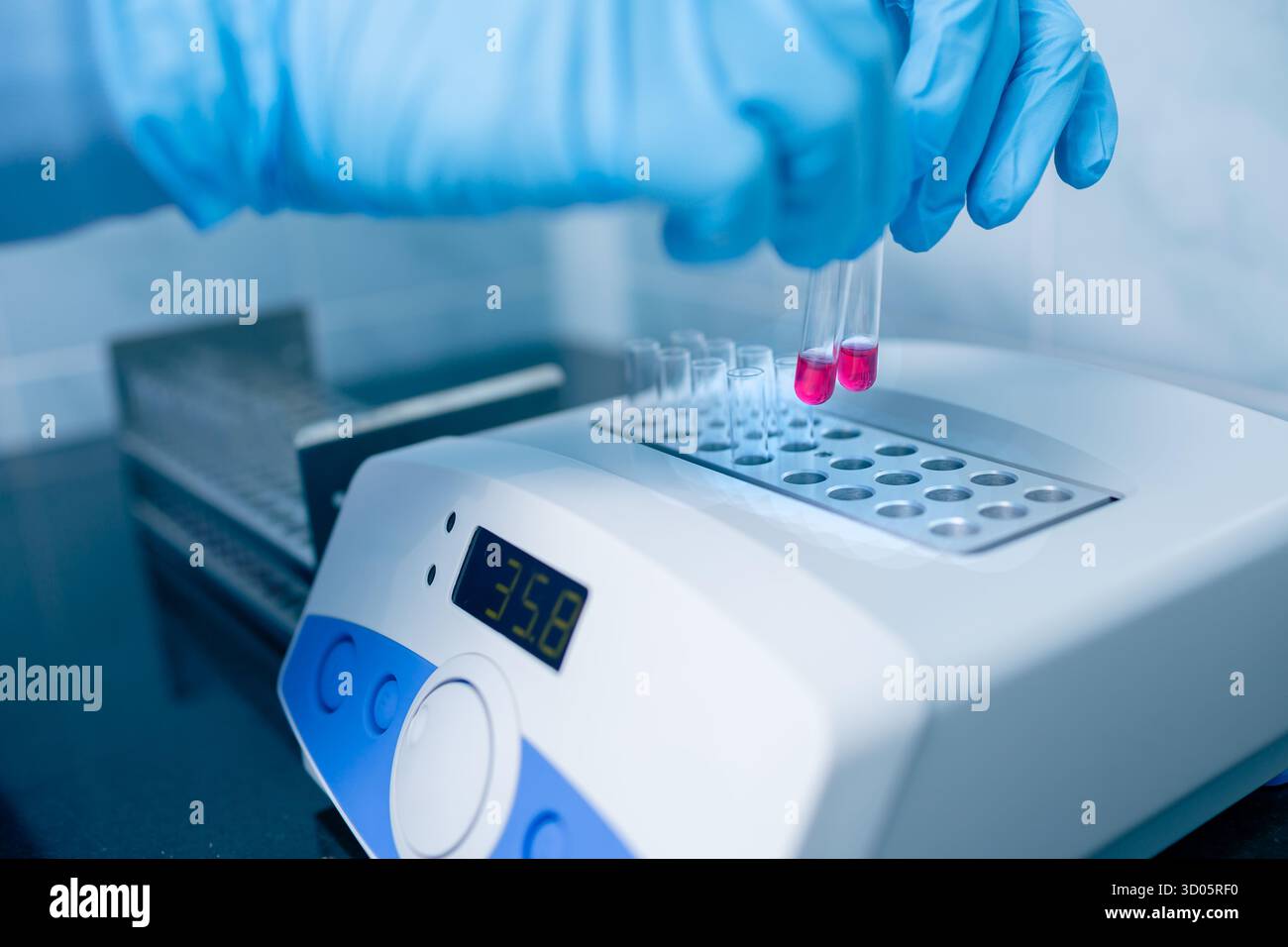 Close view of gloved hands placing reagent tubes into a digital dry ...