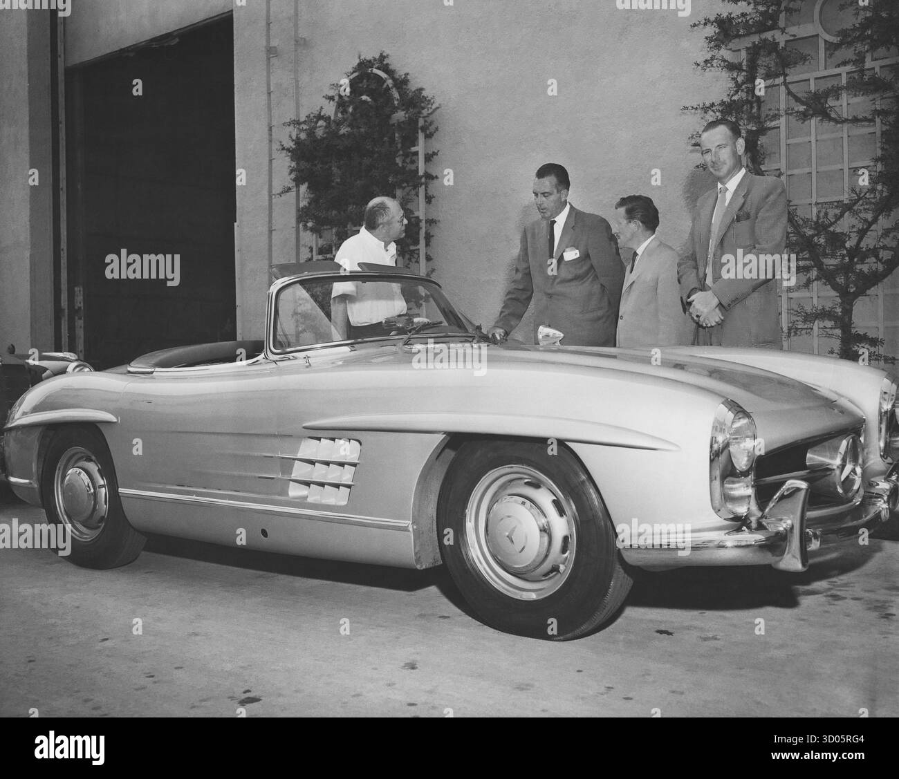 Three sales men talking to a male customer about a classic Mercedes ...
