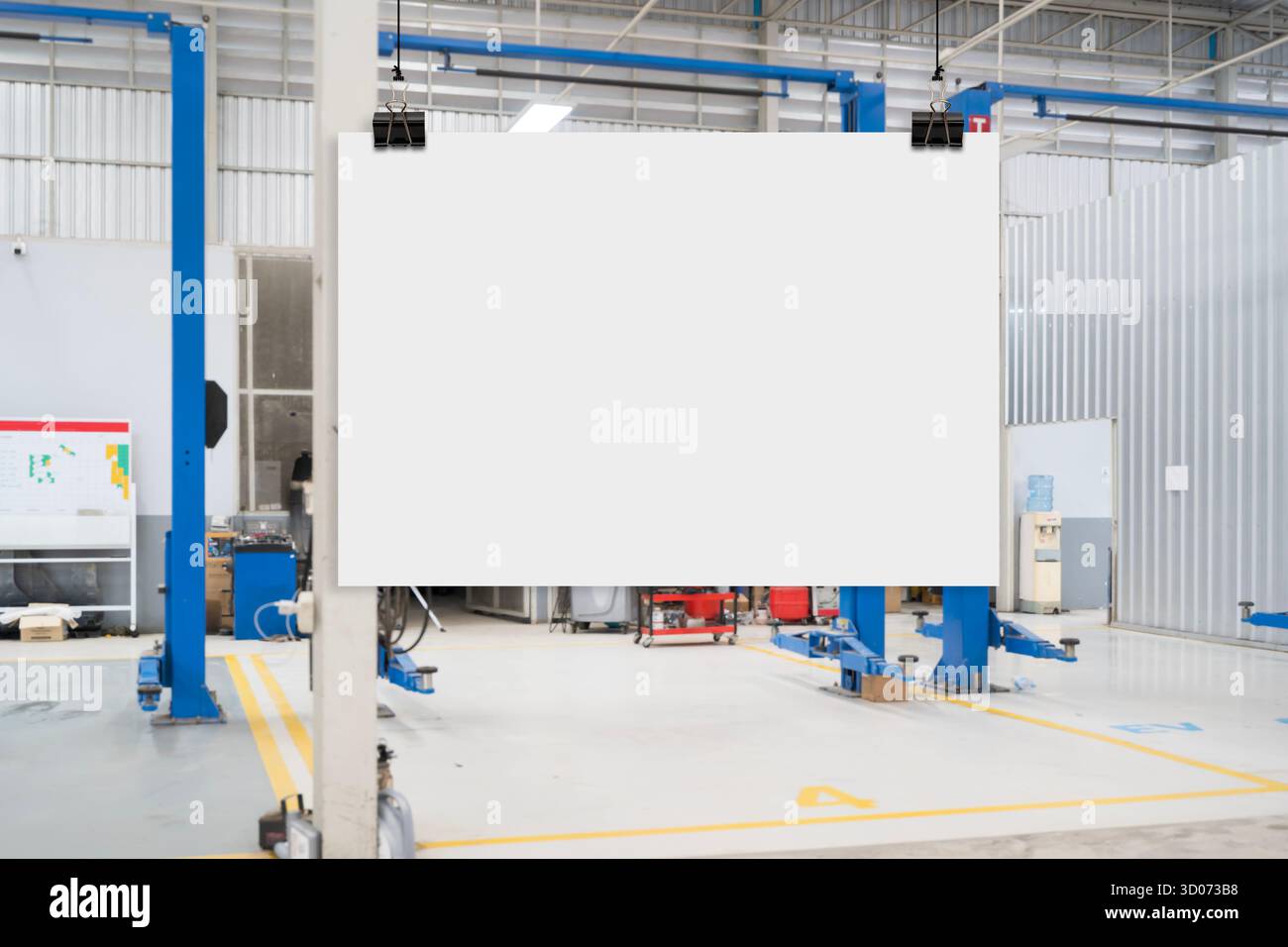Blank white board hanging in modern industrial workshop or automotive ...