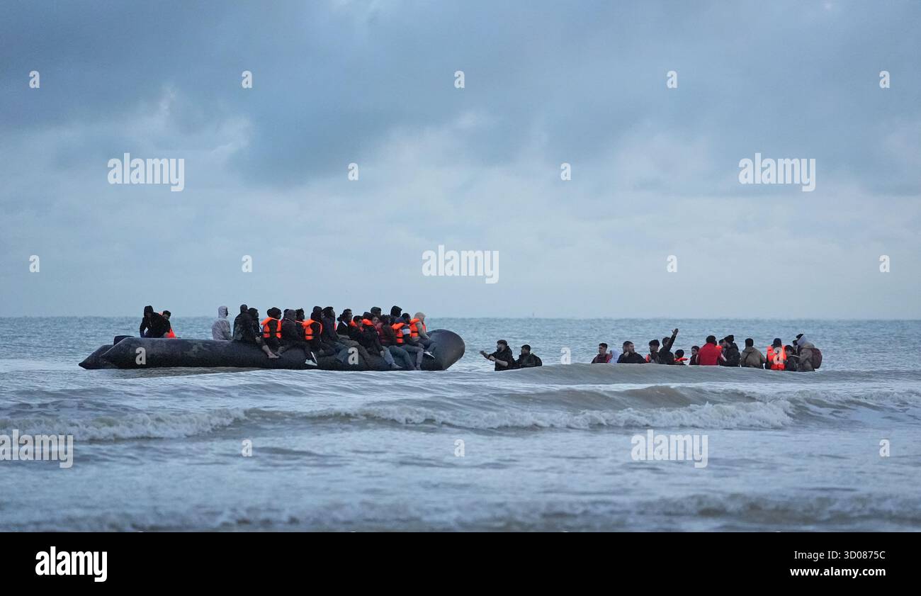 People thought to be migrants wade through the sea to board a small ...
