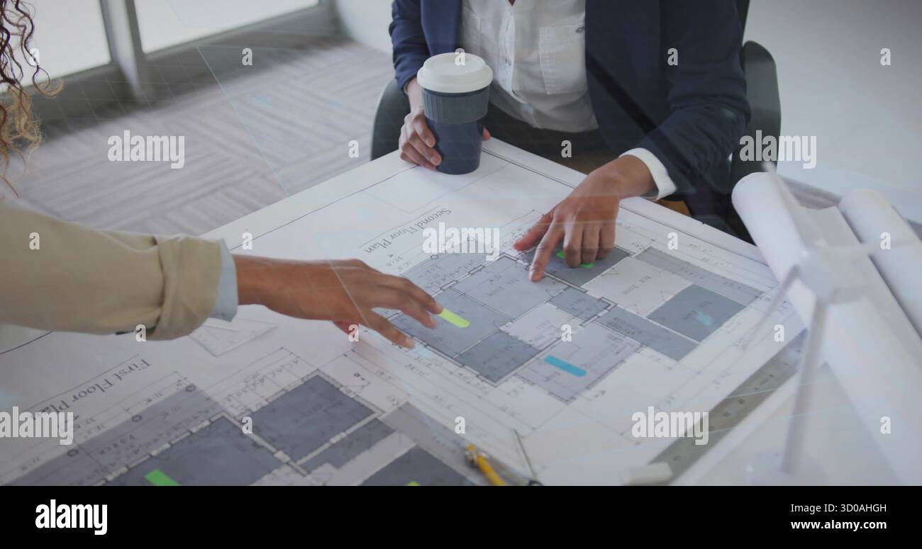 Marking architectural floor plans, two women in blazers using colored ...
